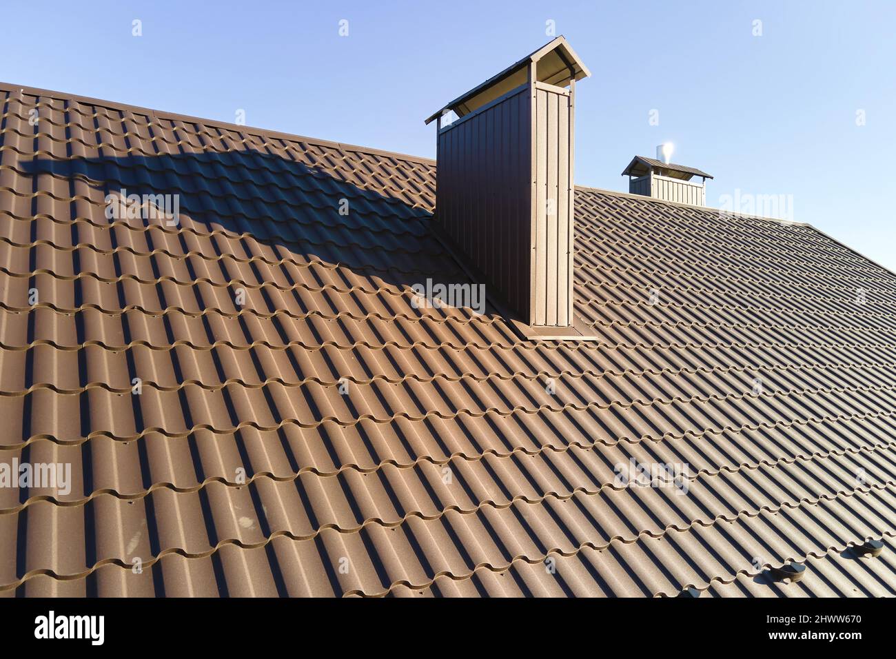 Chimney on house roof top covered with metallic shingles under ...