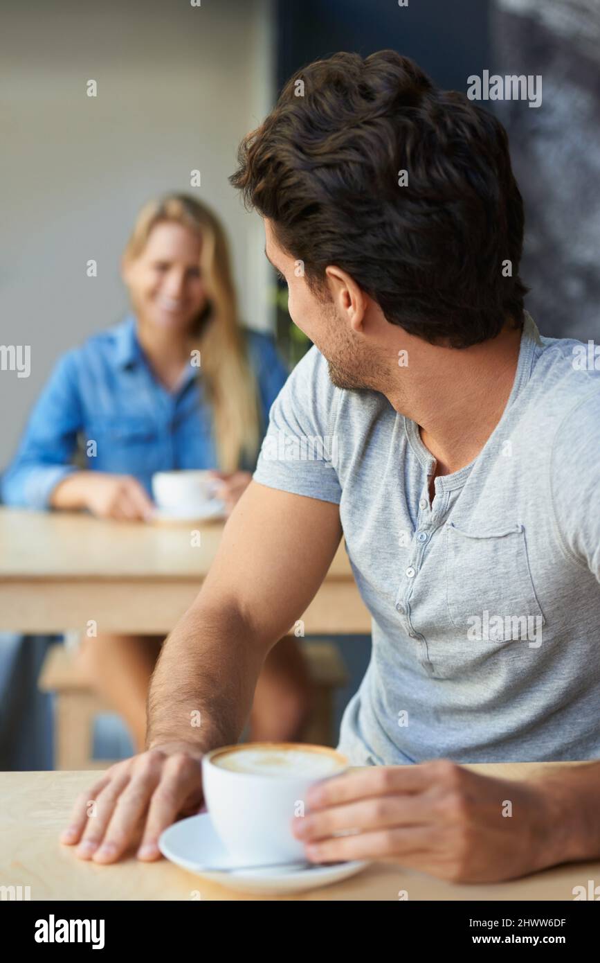 Flirting from afar. A young man in a coffee shop looking back to see ...