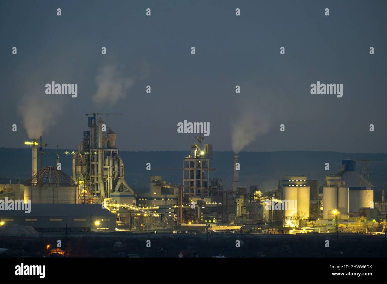 Illuminated cement plant with high factory structure and tower cranes ...