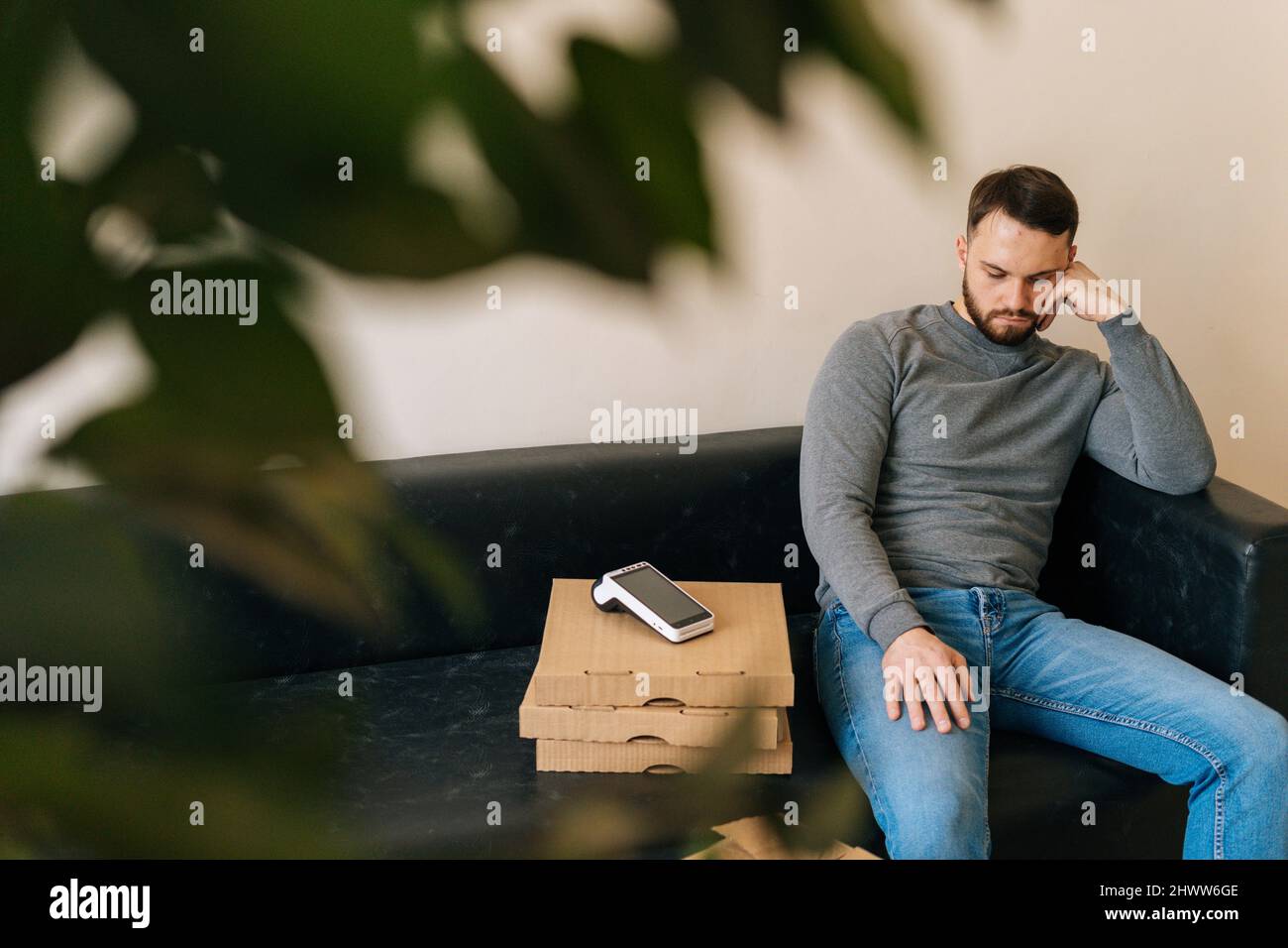 Tired bored delivery man waiting customer while sitting on sofa with ...