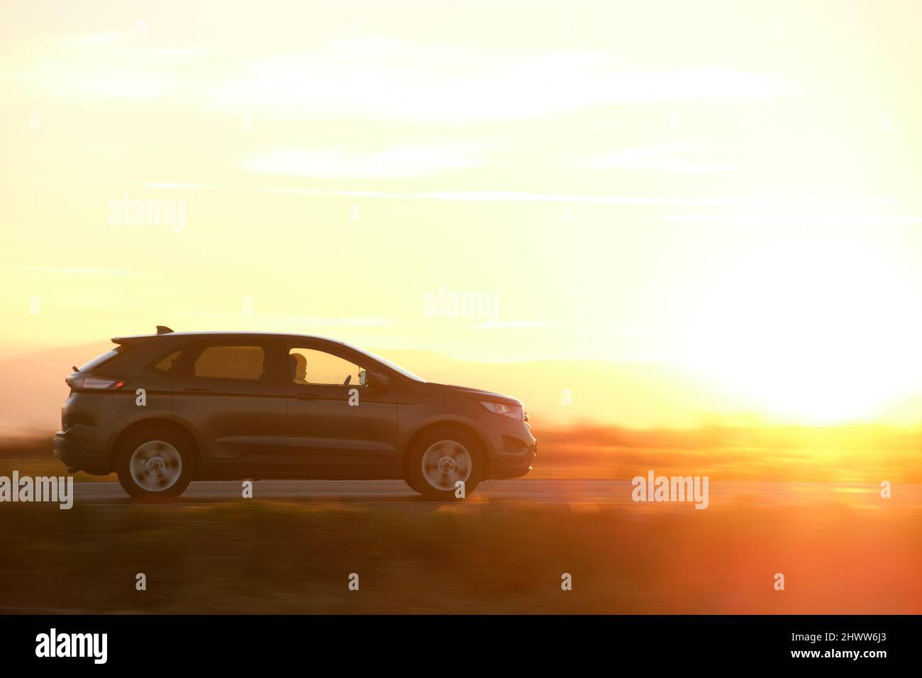SUV car driving fast on intercity road at sunset. Highway traffic in ...