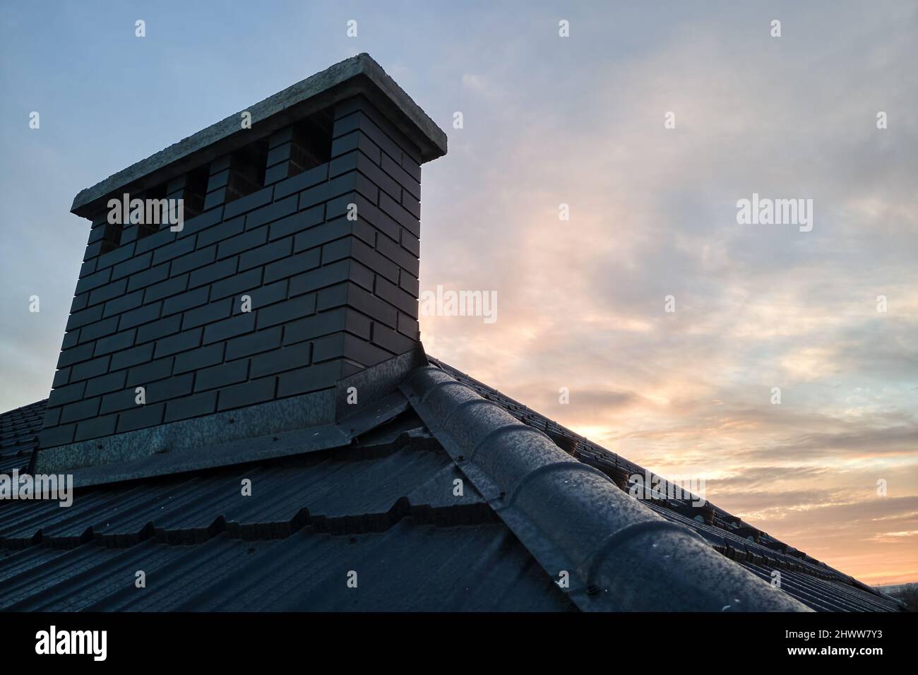 Chimney on house roof top covered with metallic shingles under ...