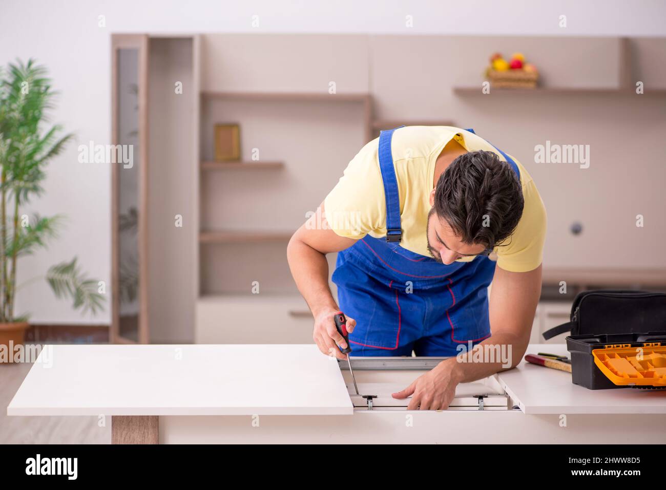 Young carpenter repairing table at home Stock Photo - Alamy