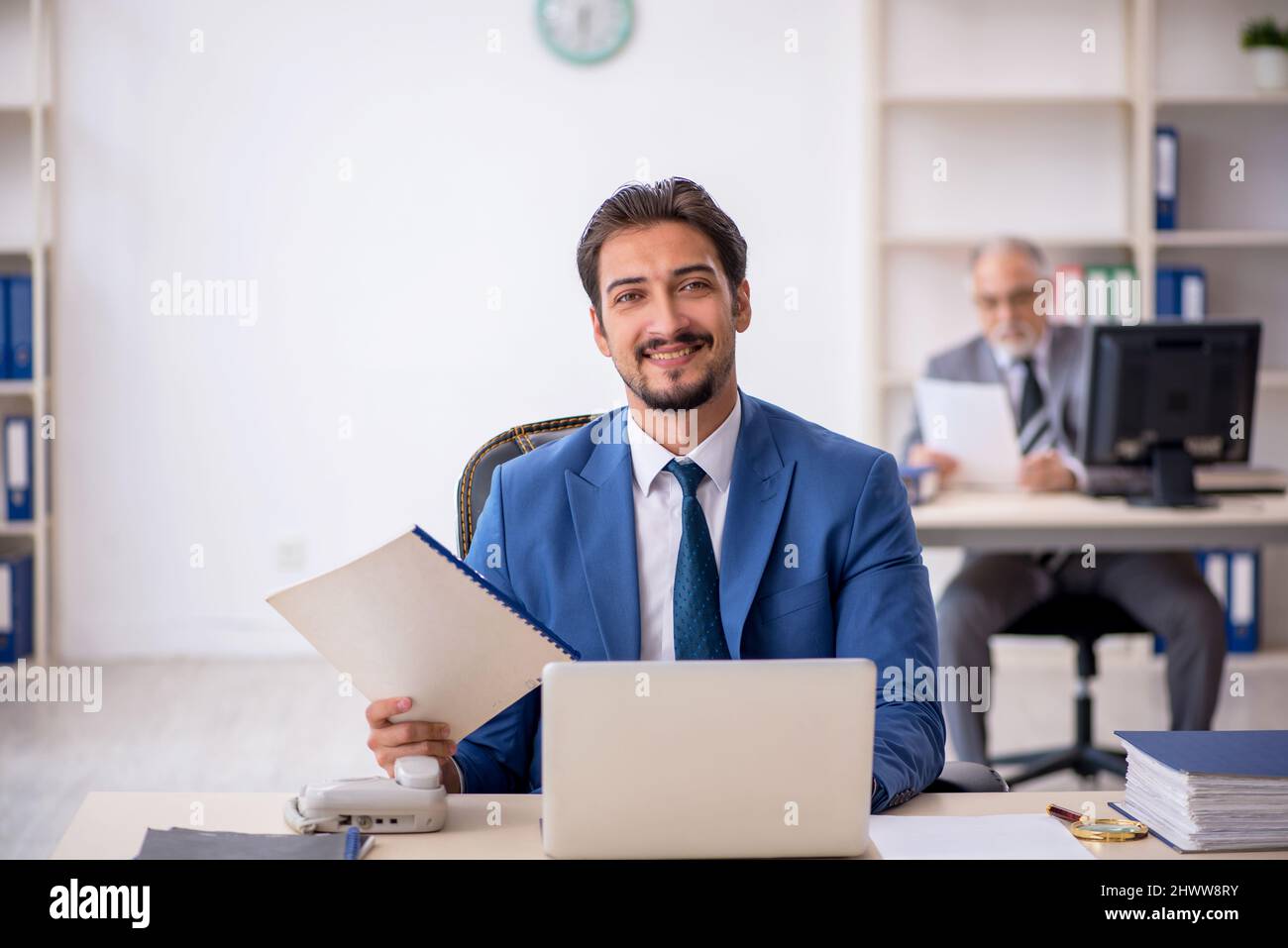 Old boss and young employee working at workplace Stock Photo - Alamy