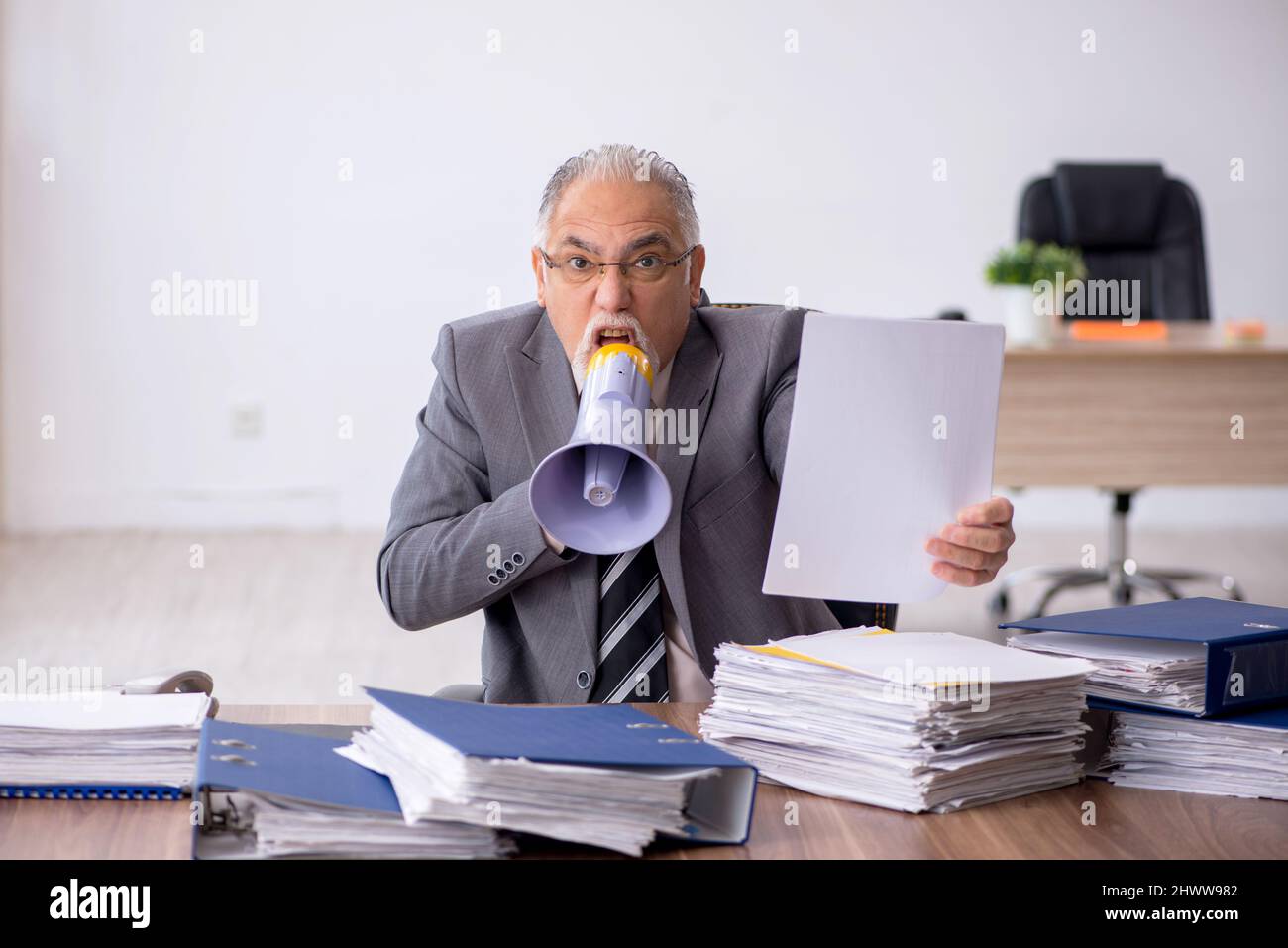 Old male boss holding megaphone at workplace Stock Photo - Alamy