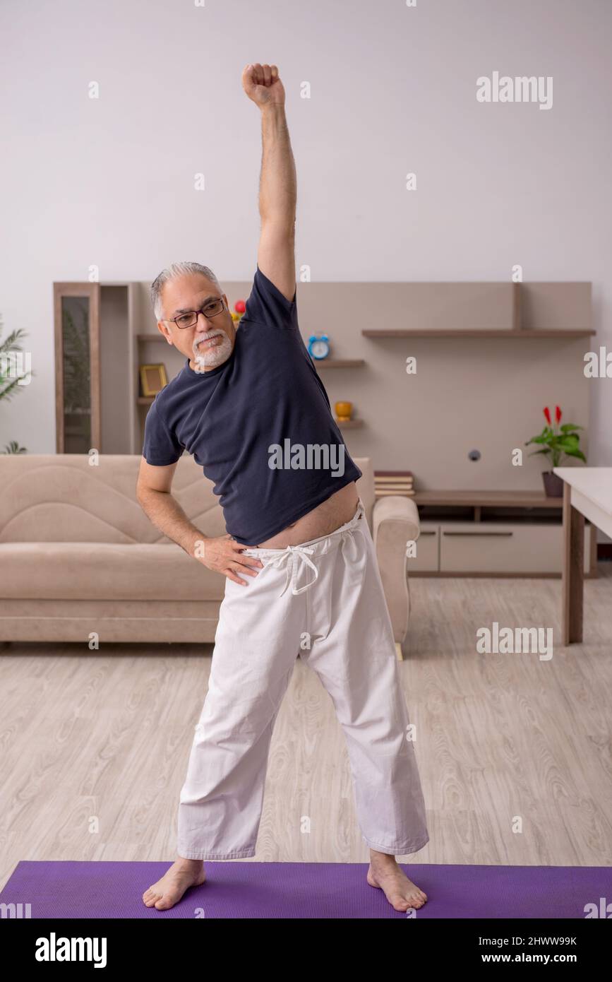 Old man doing sport exercises indoors Stock Photo - Alamy