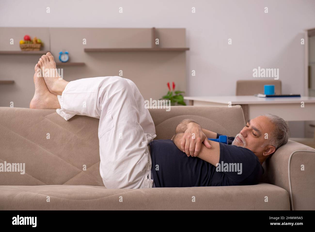 Old man doing sport exercises indoors Stock Photo - Alamy