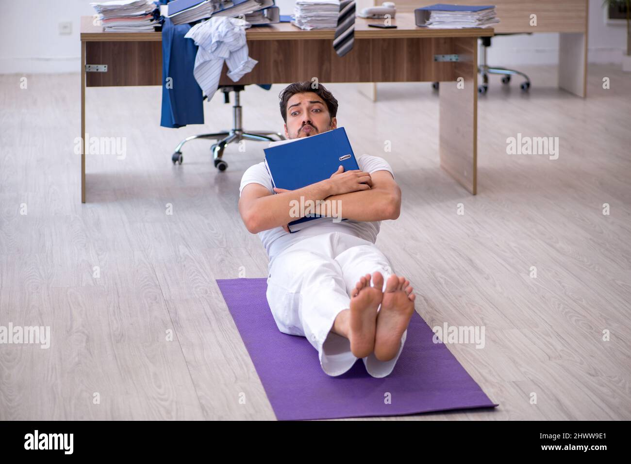 Young businessman employee doing sport exercises at workplace Stock ...