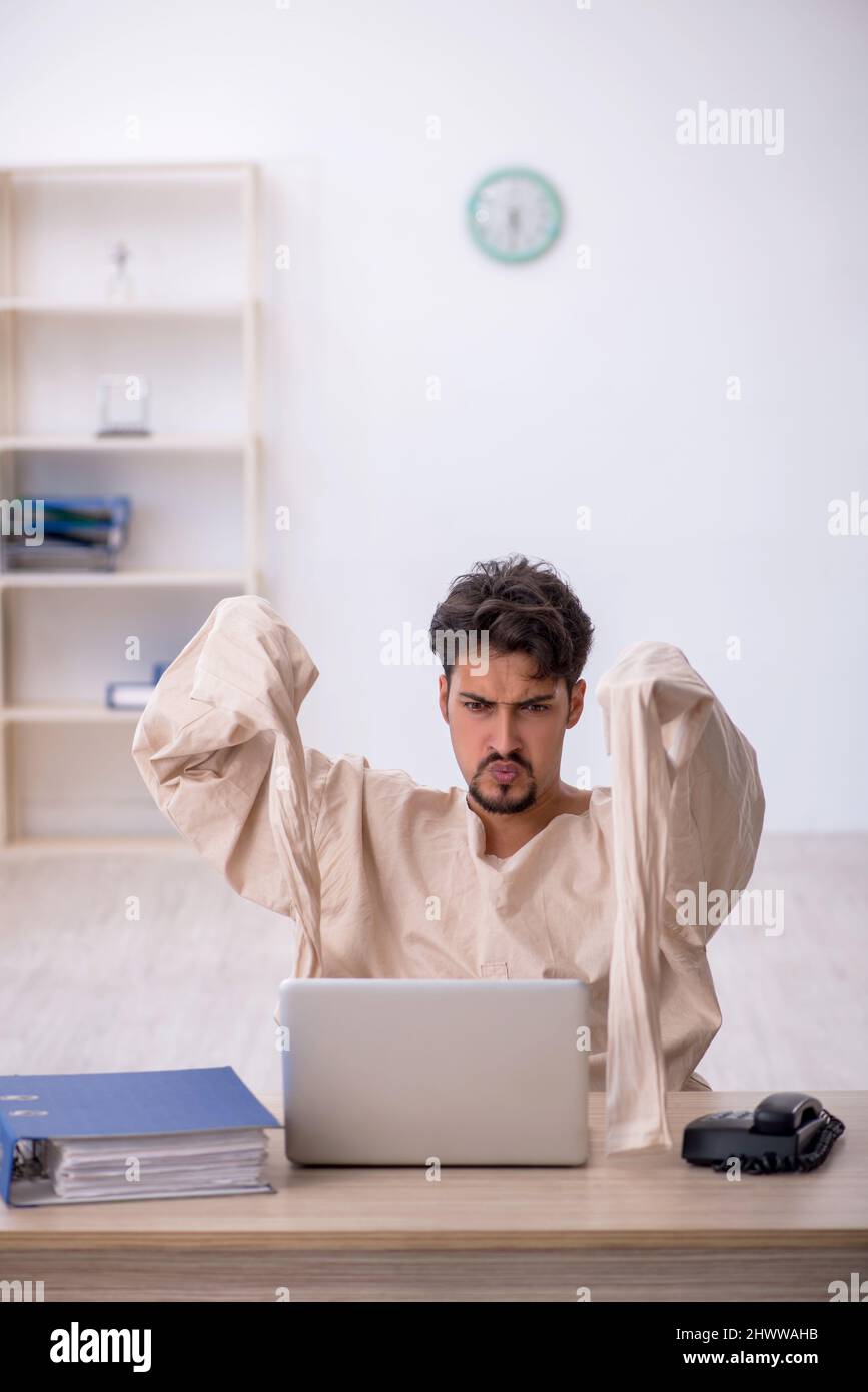 Crazy young male employee in straitjacket at the office Stock Photo - Alamy