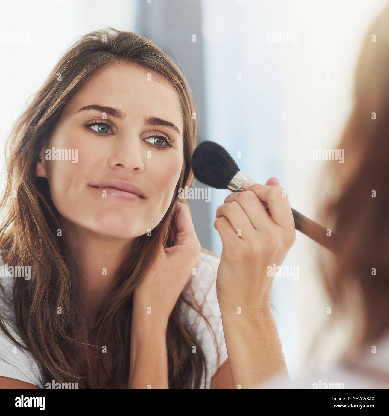 Blending her makeup for a natural look. Shot of a beautiful young woman ...