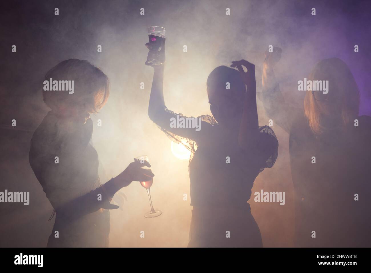 Backlit shot of young women dancing at party, elegant silhouettes in ...