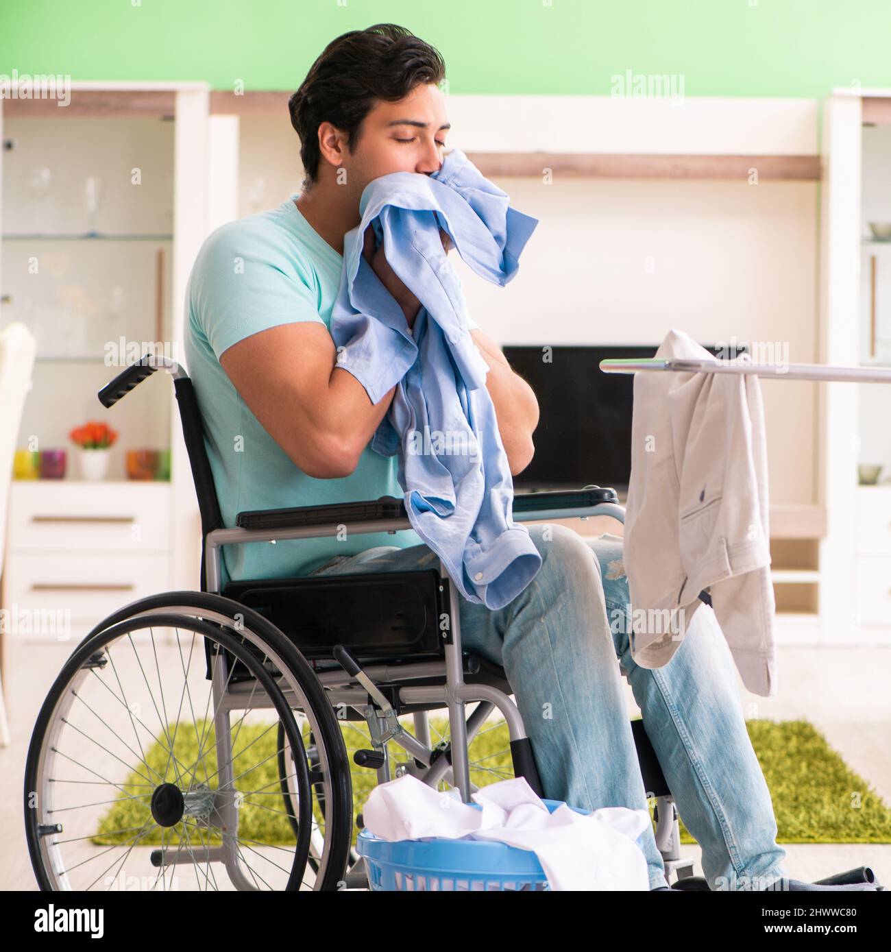 The disabled man on wheelchair doing laundry Stock Photo - Alamy