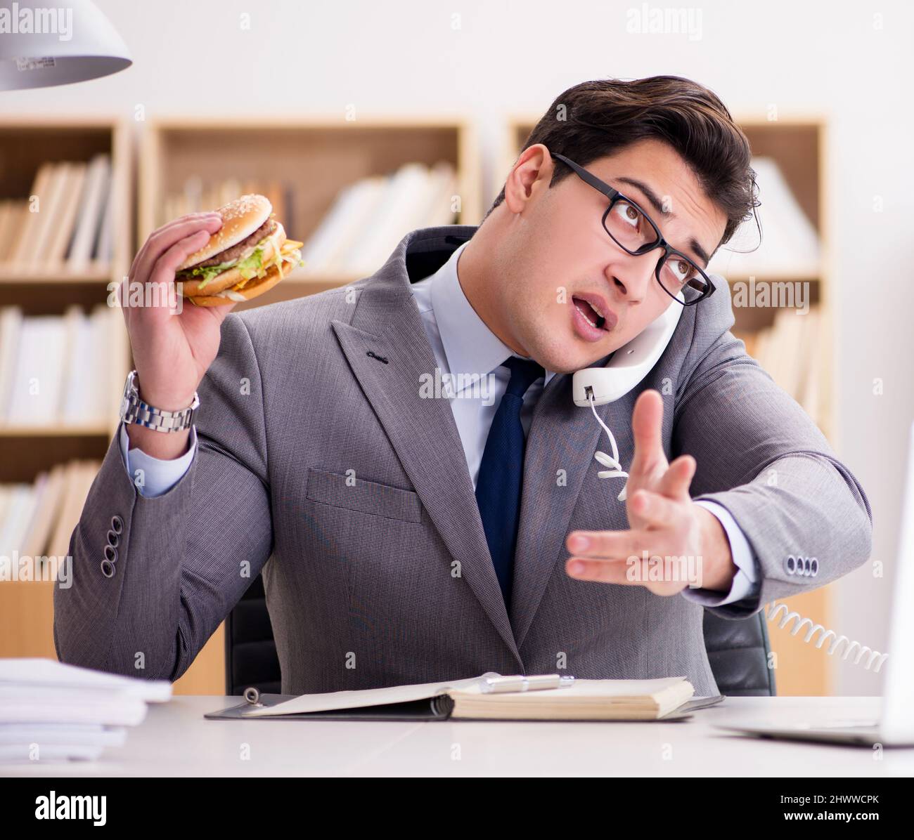 The hungry funny businessman eating junk food sandwich Stock Photo - Alamy