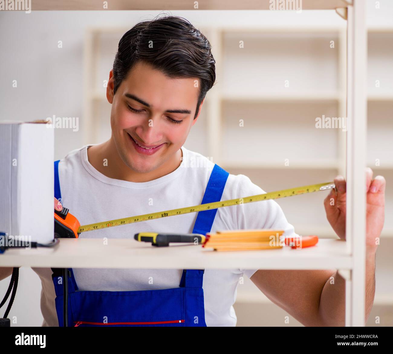 The worker man repairing assembling bookshelf Stock Photo - Alamy