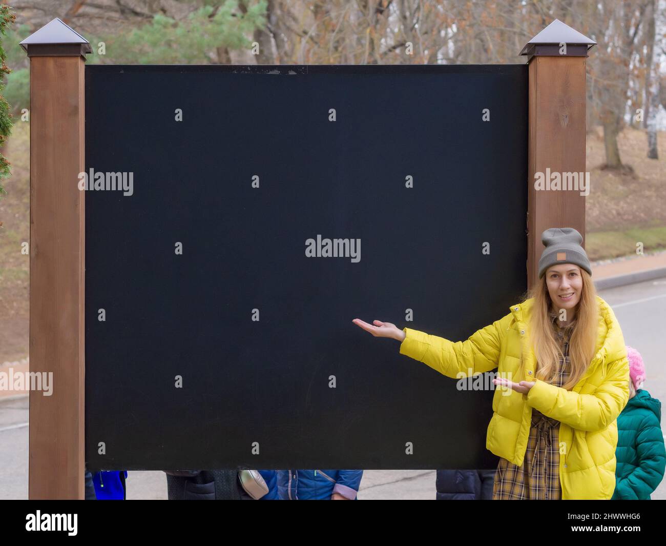 Smiling girl in yellow jacket points to an empty stand in an autumn ...