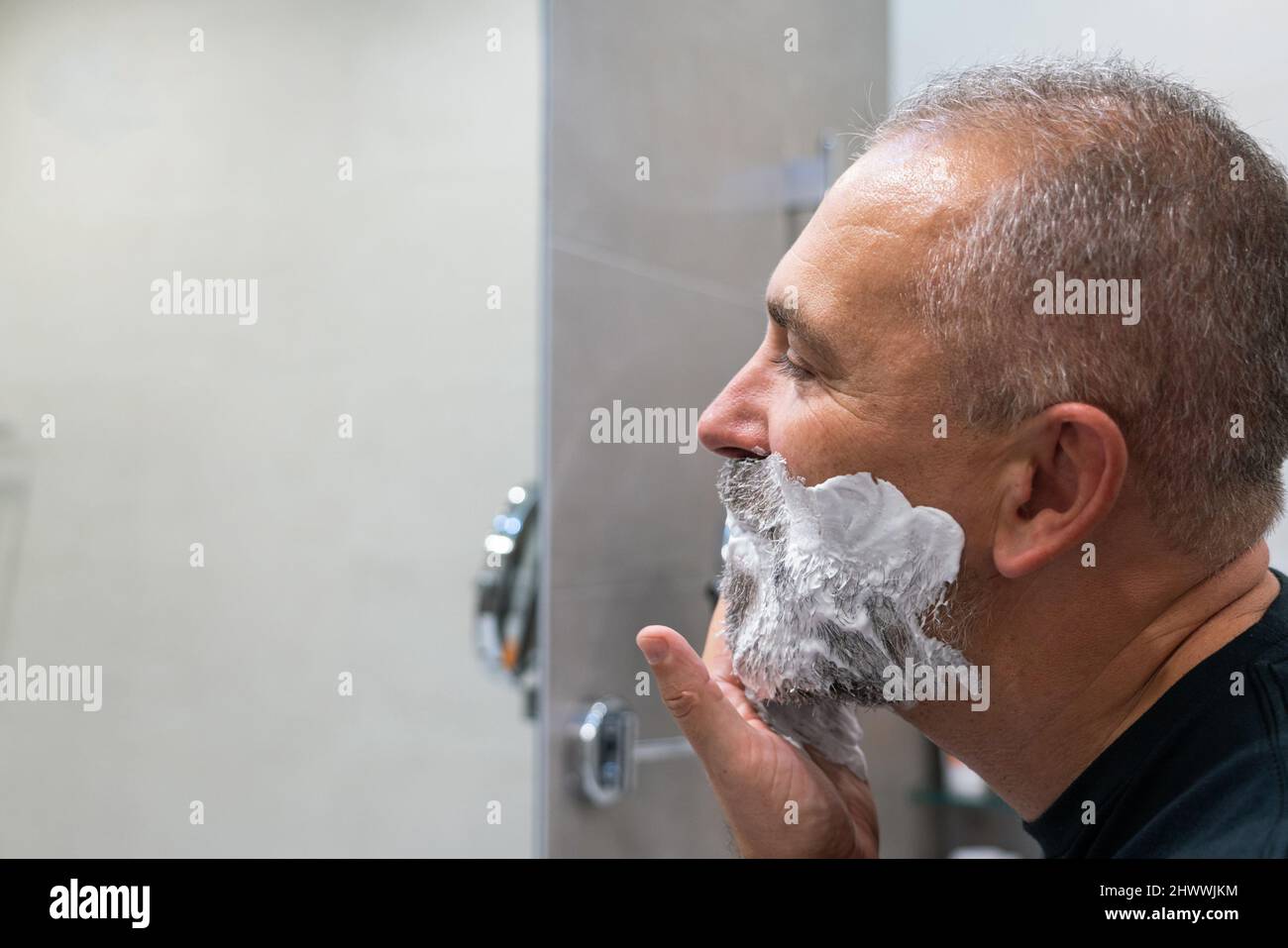 Mature handsome man applying shaving foam on his face to cut off his ...