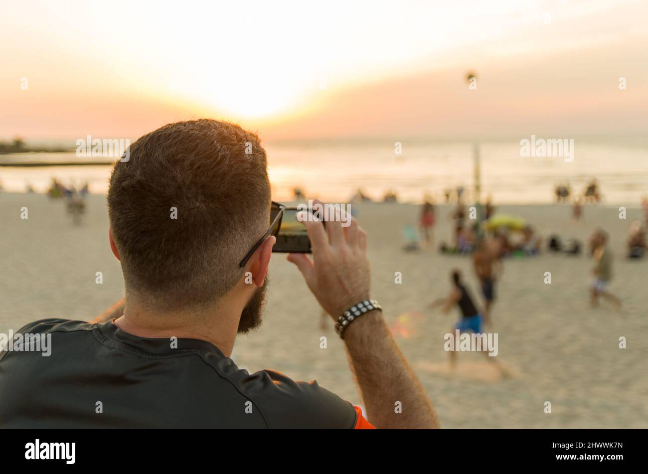 Man photographing sunset on the beach with smartphone Stock Photo - Alamy