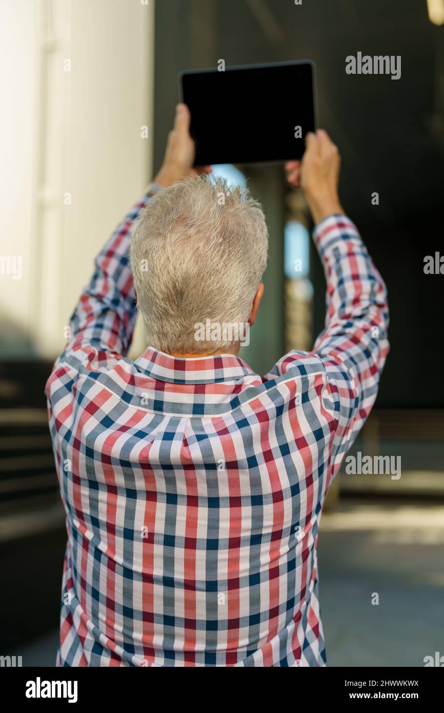 Old man holding up his tablet high above head Stock Photo - Alamy