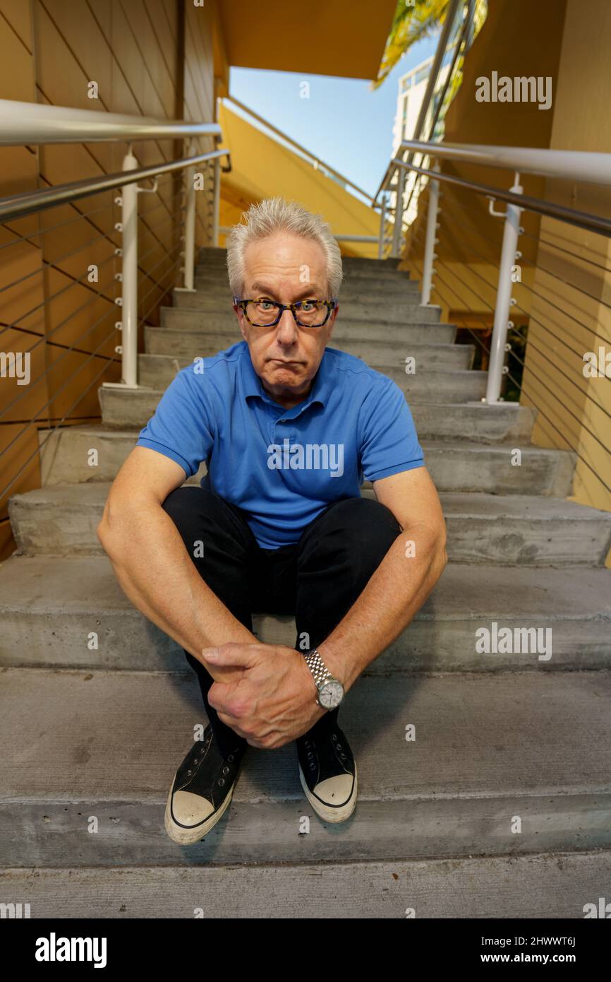 Scared expression old man sitting on a staircase Stock Photo - Alamy