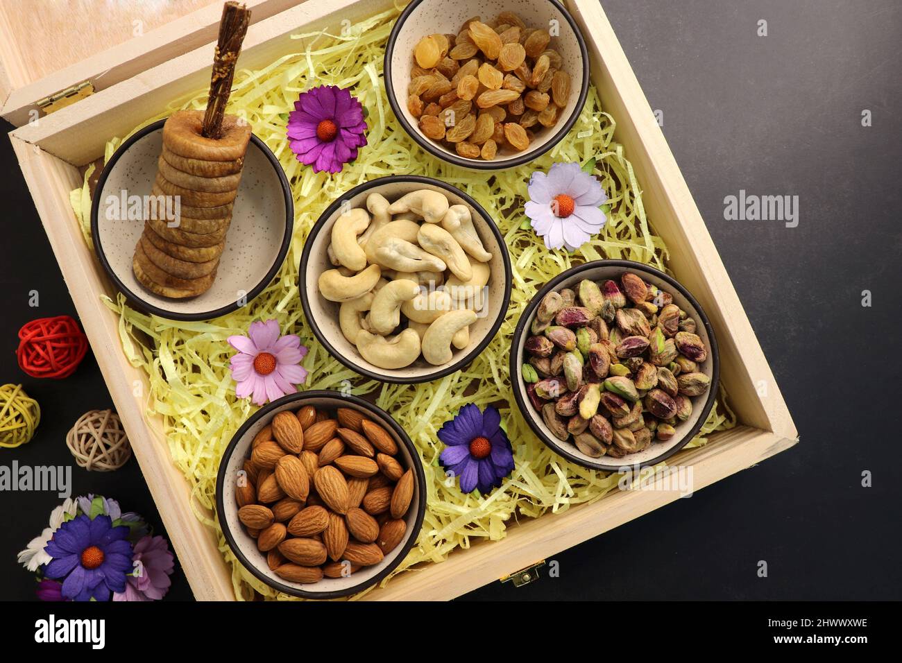 Various varieties of nuts and dried fruits are in a bowls on black ...