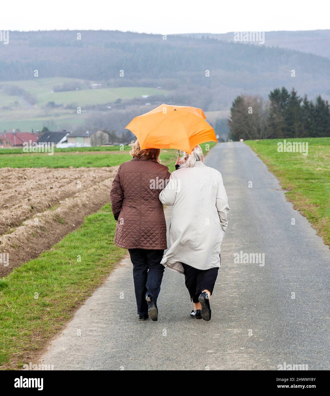 women in rain under an umbrella in rural landscape Stock Photo - Alamy