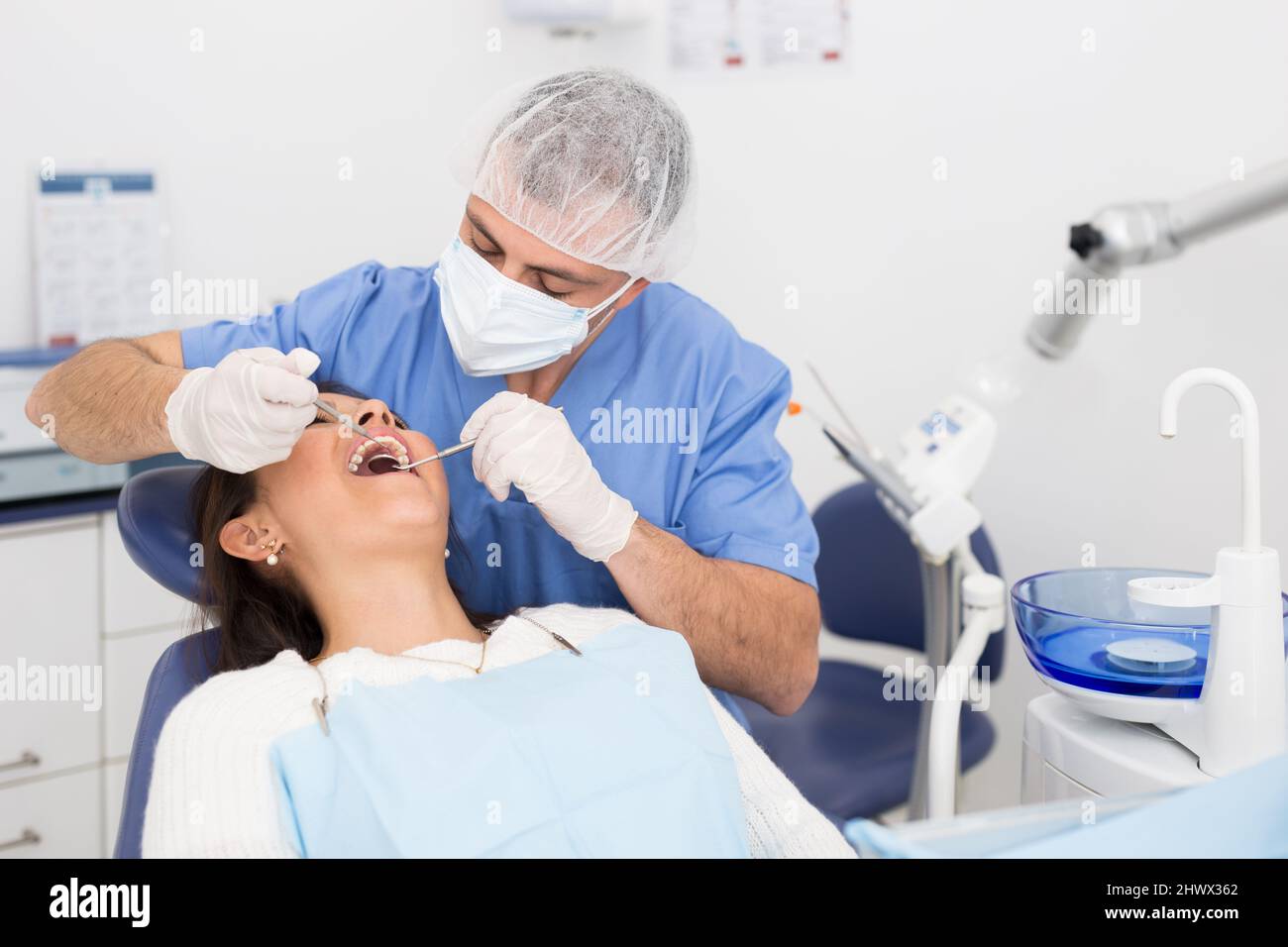 Dentist man examining a latin female patient teeth Stock Photo - Alamy
