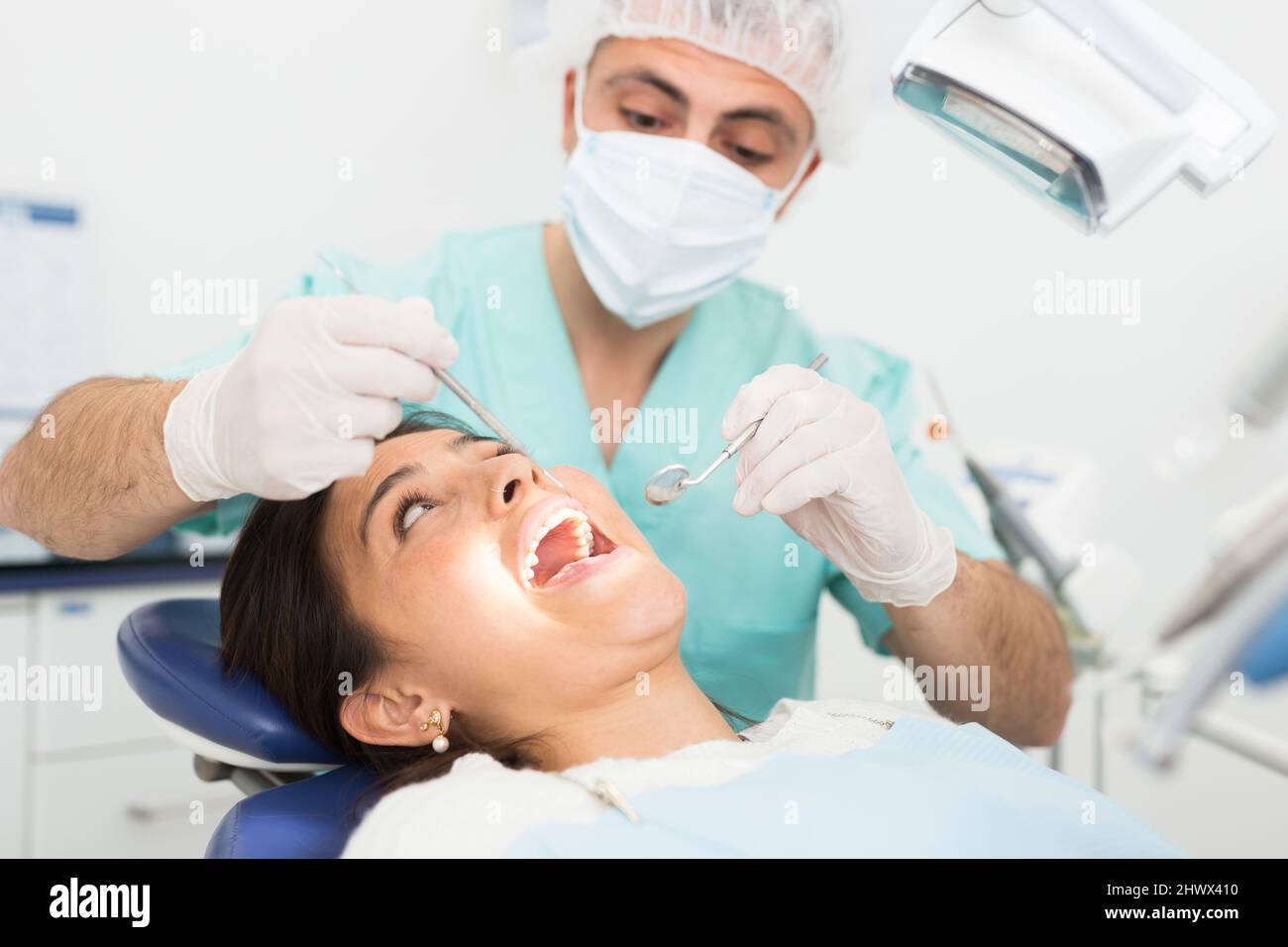 Dentist man examining a latin female patient teeth Stock Photo - Alamy