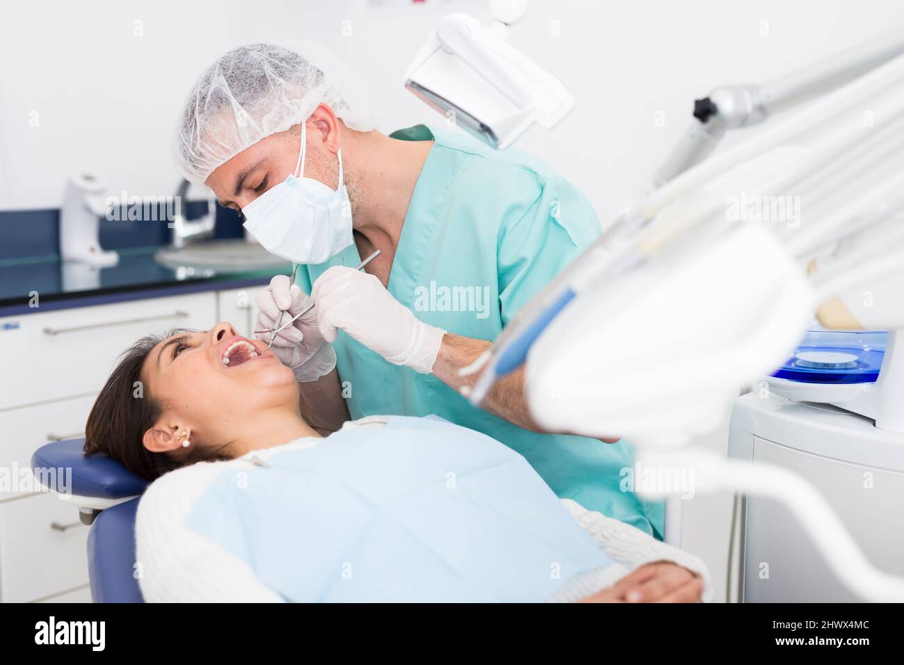 Dentist man examining a latin female patient teeth Stock Photo - Alamy