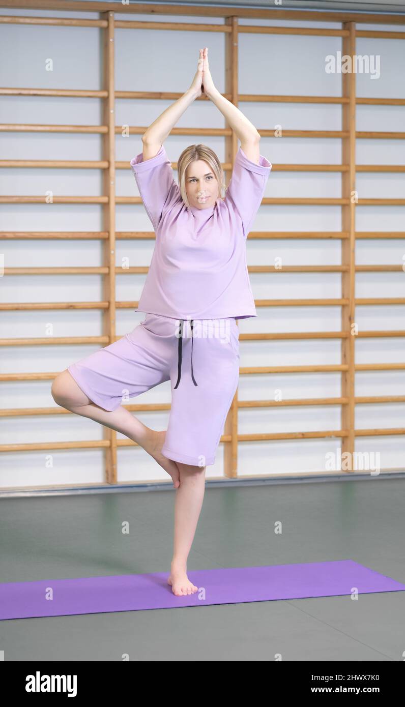 Full length front view of a woman standing on one leg while practicing ...
