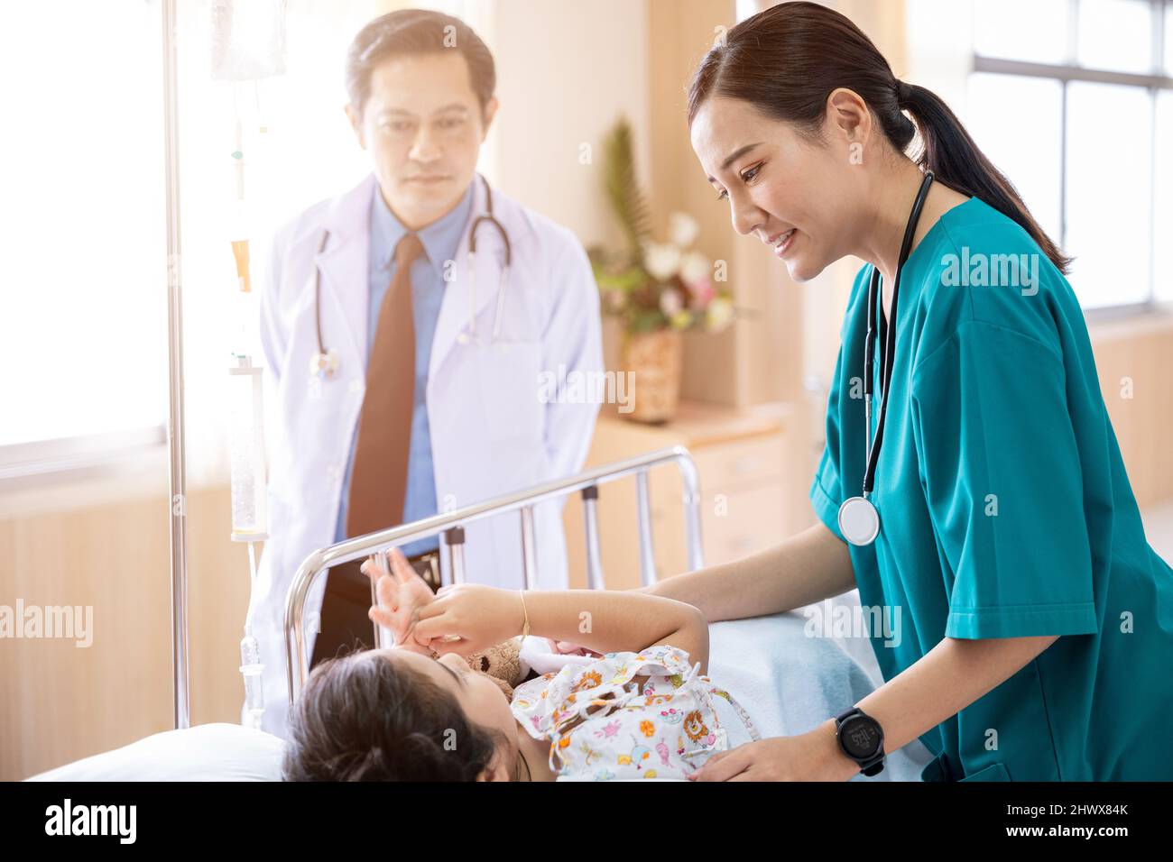 Pediatrician visiting parents and child in hospital bed ward, doctor ...