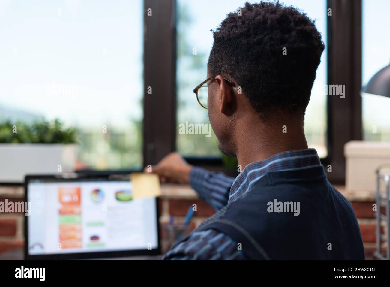 Over shoulder view of startup owner working at desk sticking yellow ...