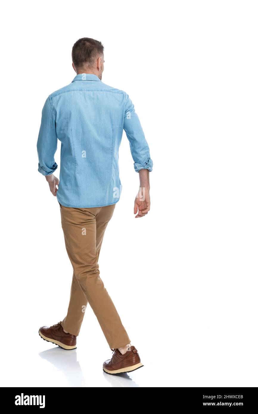 back view of man with blue jeans shirt and chino pants walking and ...