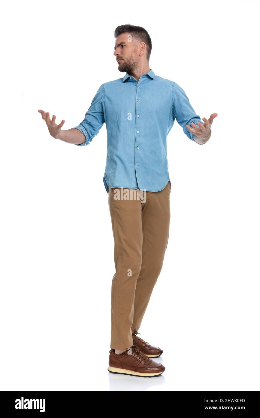 casual man in denim shirt looking behind over shoulder and opening arms ...