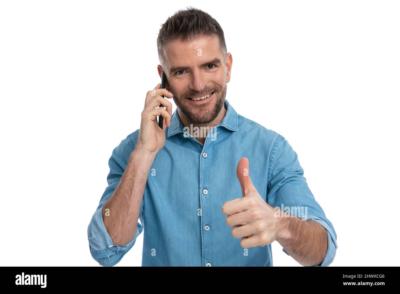 portrait of happy man speaking on the phone and showing thumbs up sign ...