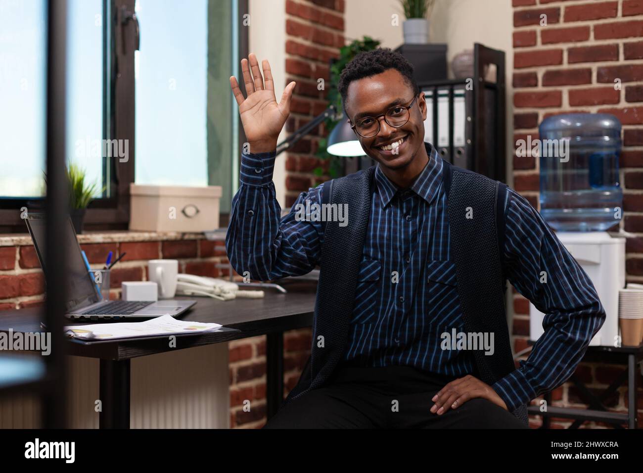 Smiling startup employee with glasses posing casual waving hello ...