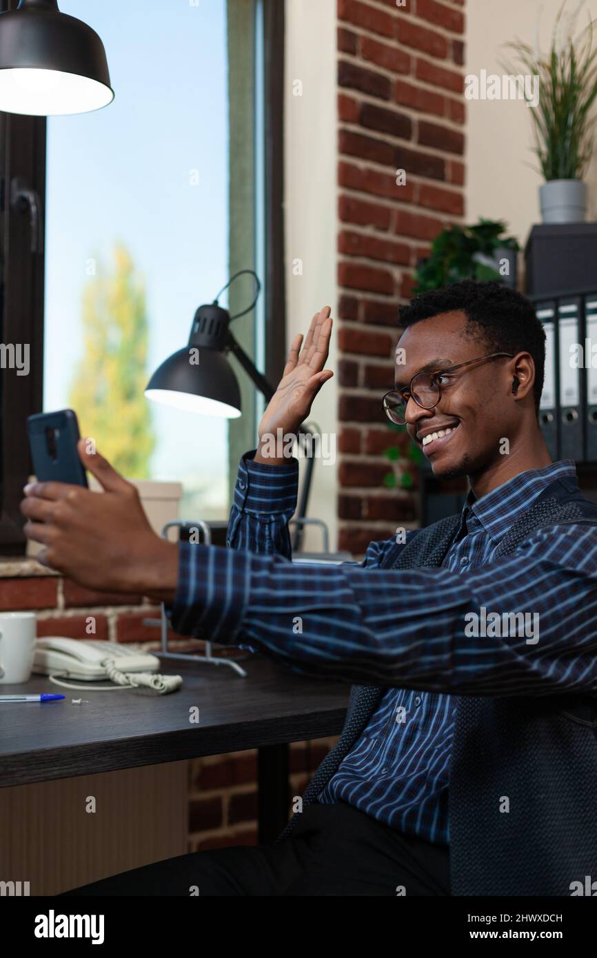 Smiling startup employee waving hello presenting himself in online ...