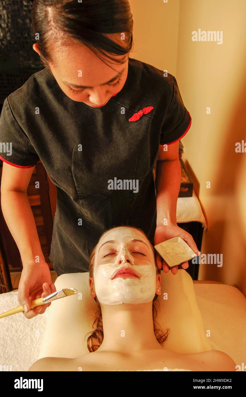 A beauty therapist applies a facial mask to her clients face.(MODEL ...
