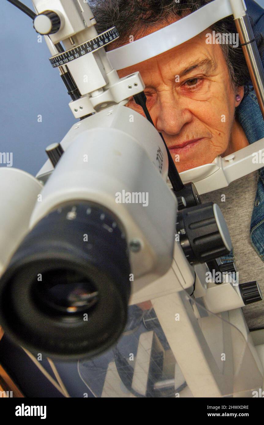 An optometrist examines a patient’s eye with a slit lamp. The ...