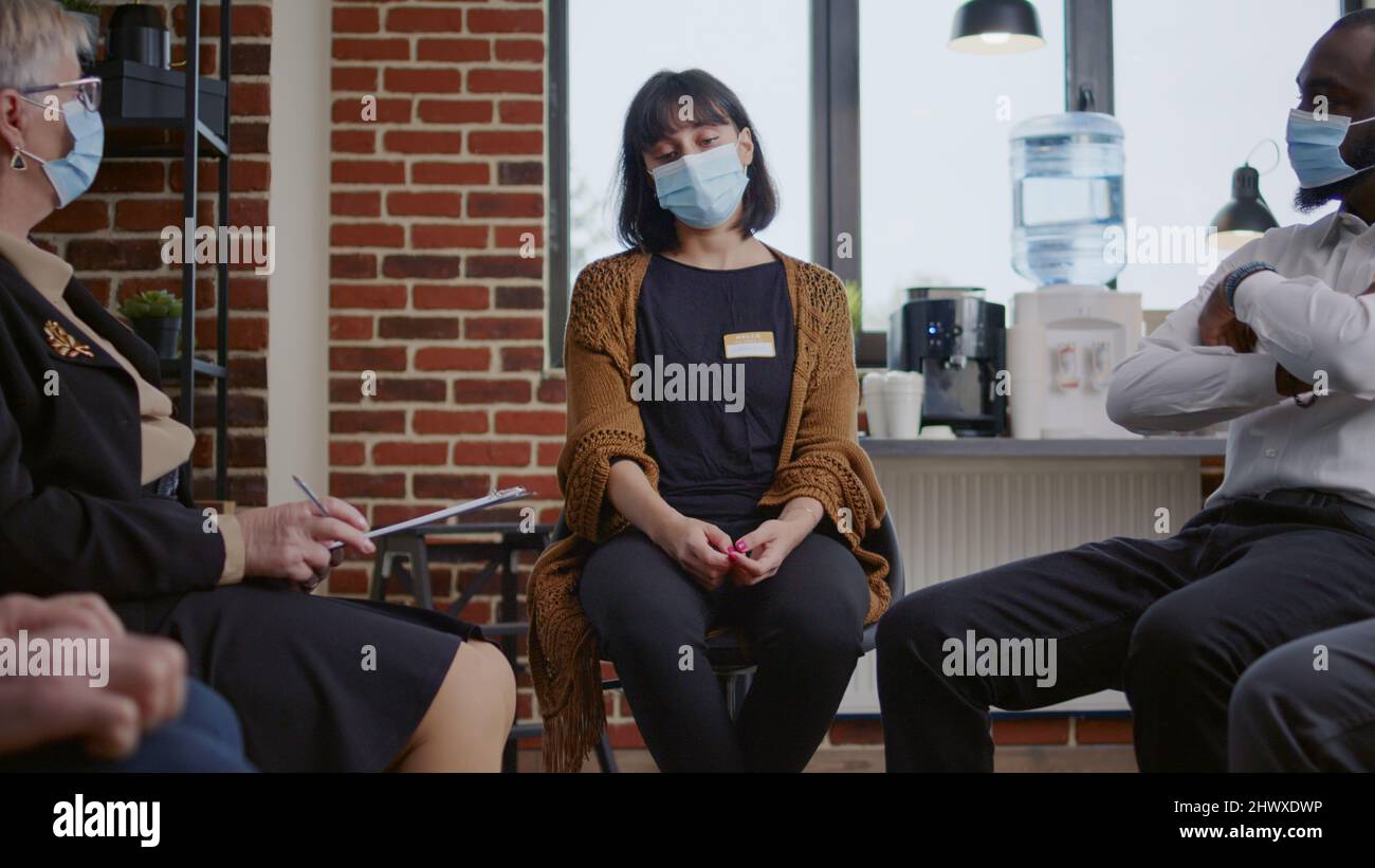 Sad woman crying at aa therapy meeting in front of group of people ...