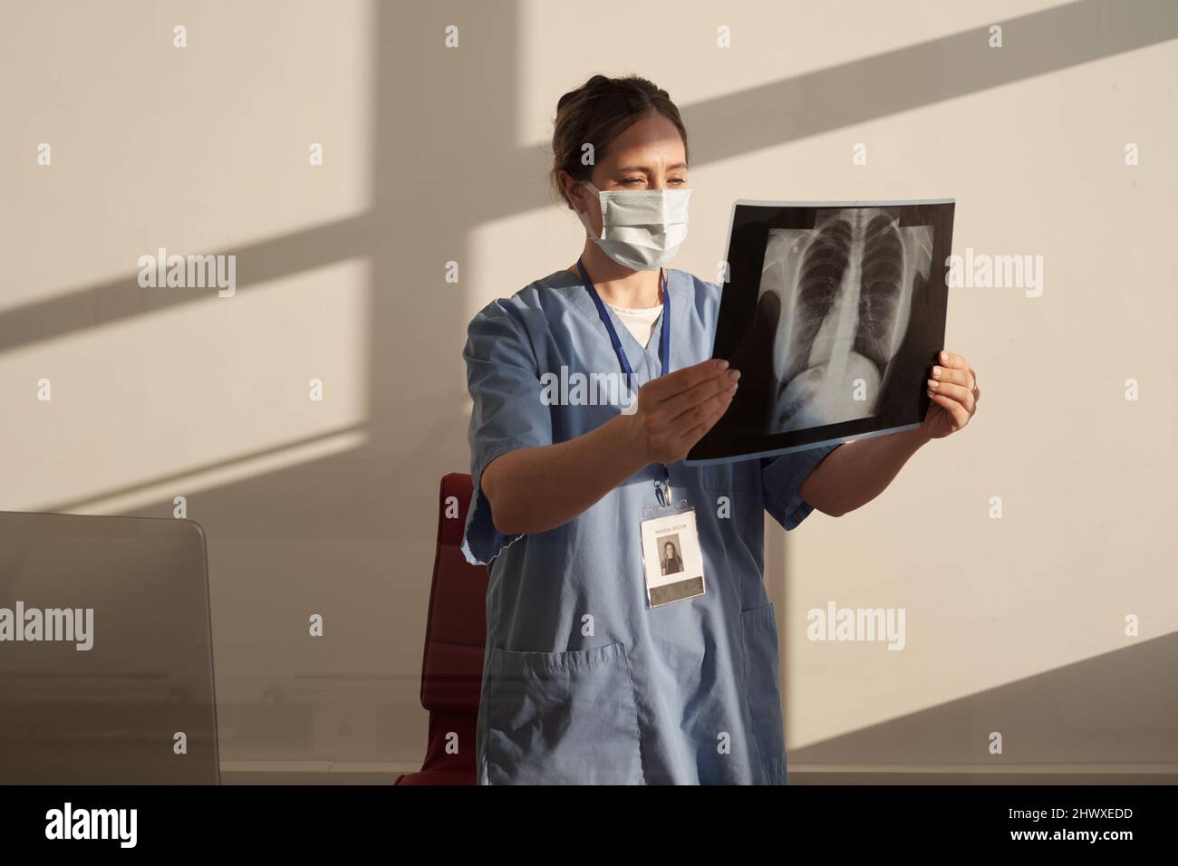 Young serious female radiologist looking at x-ray image after ...