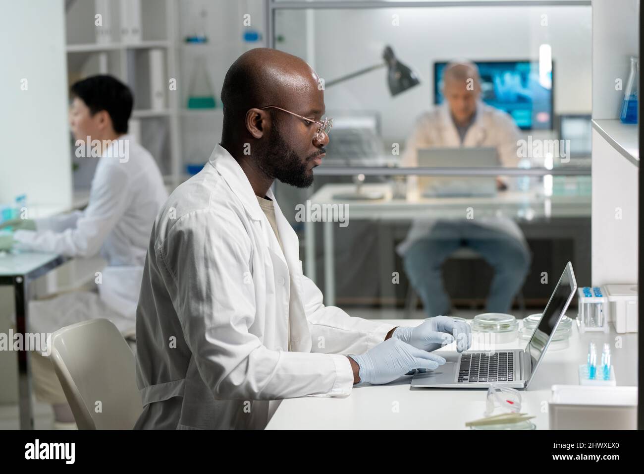 Side view of young African American researcher in lab coat and surgical ...