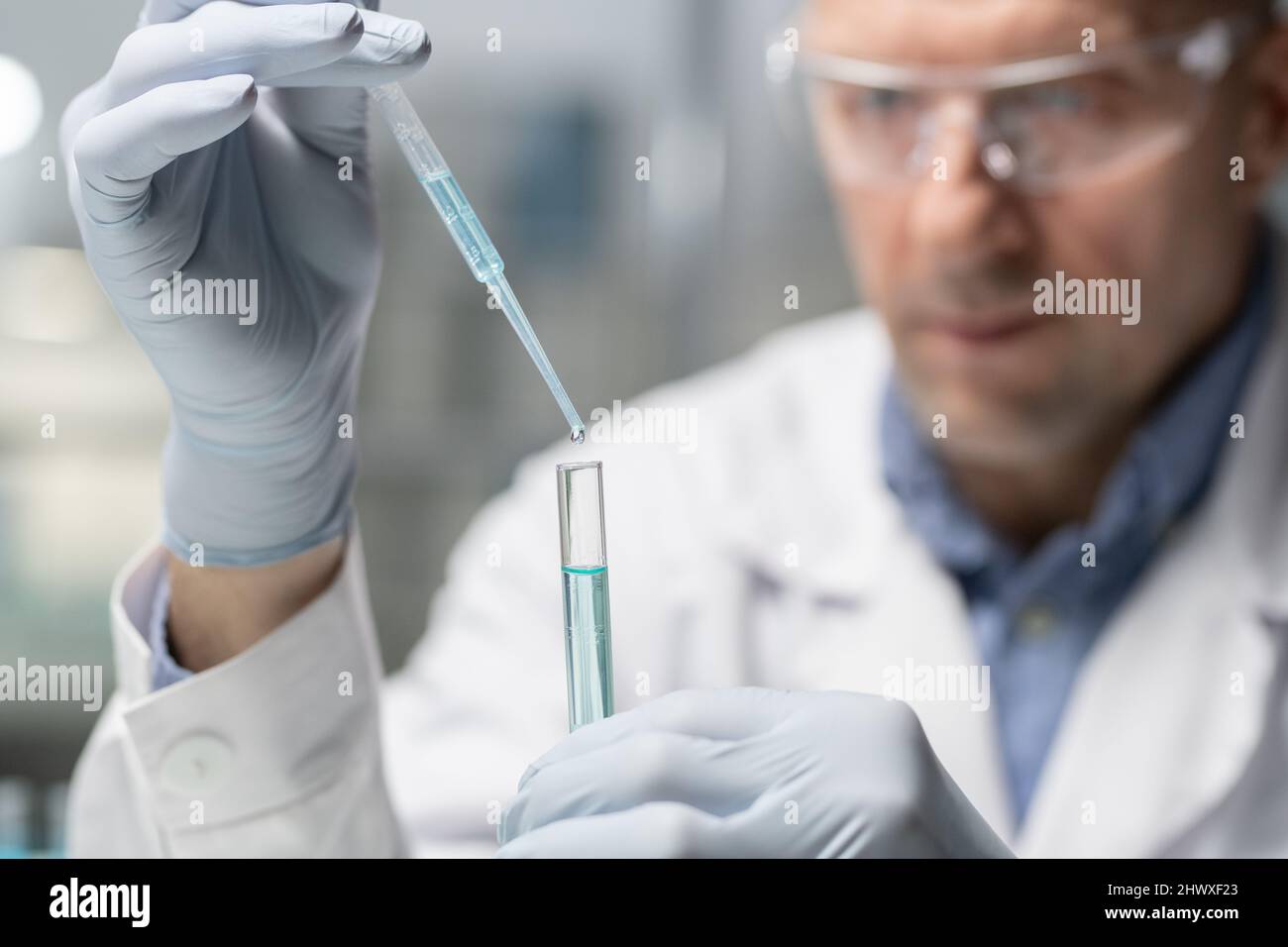 Serious scientist with flask and pipette making experiment with liquid ...