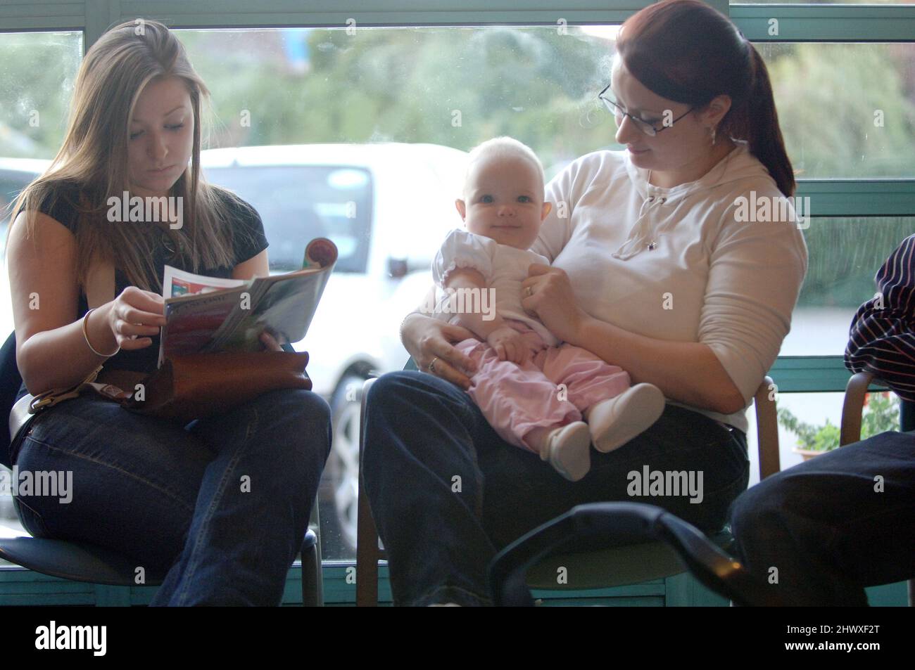 Two young women and a baby wait for a consultation in a doctor's ...