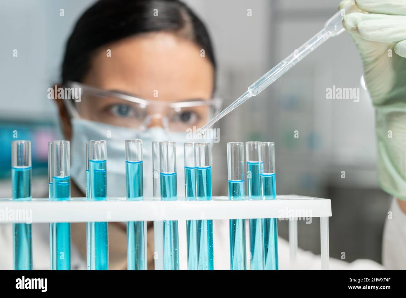 Part of face of young female lab worker in protective mask and ...