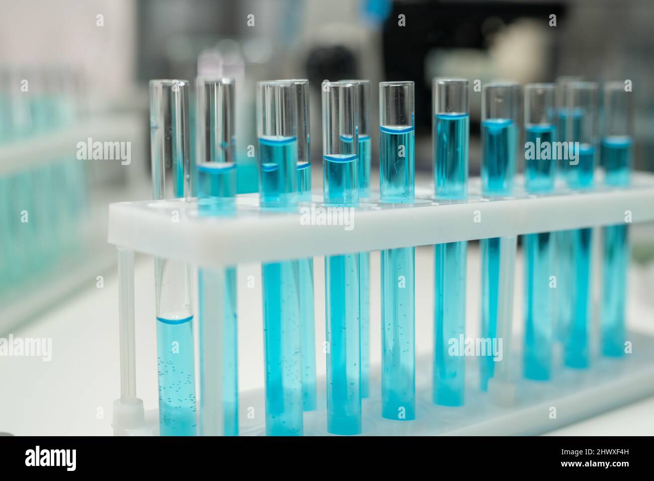 Row of several flasks or test tubes with blue liquid on workplace of ...