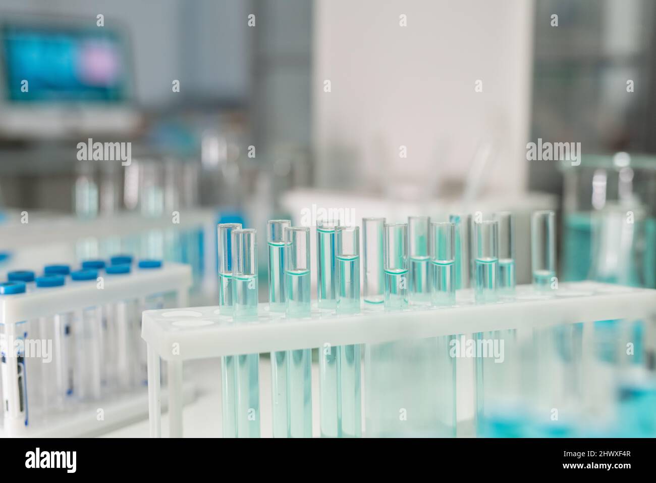 Group of test tubes containing light blue liquid substance standing on ...