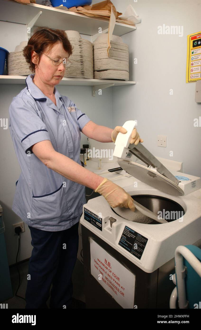 Hospital orderly in sluice room using disposable bedpan machine.(MODEL ...