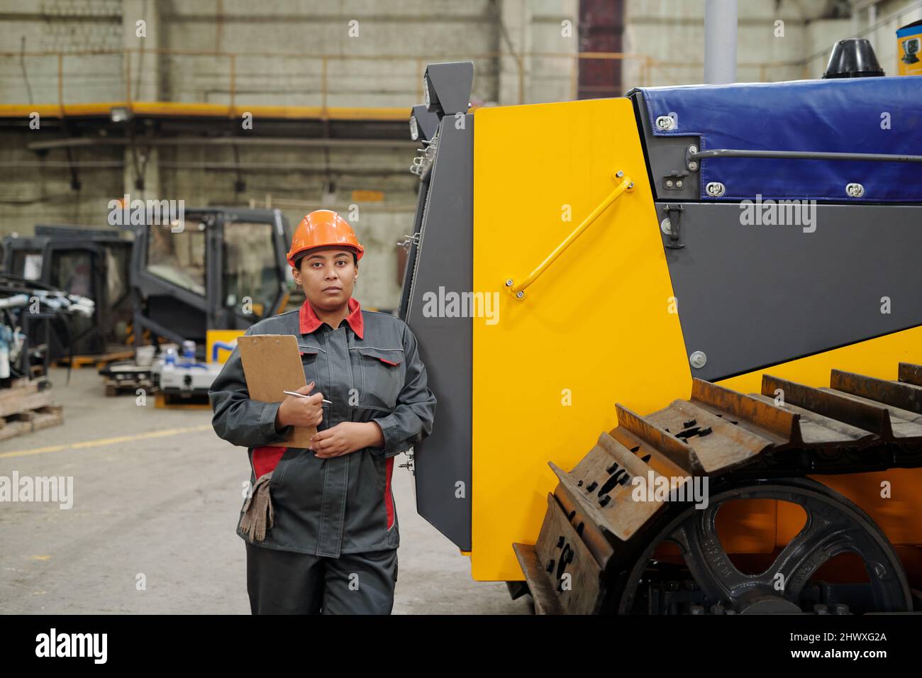 Young confident staff of large modern factory standing by huge ...