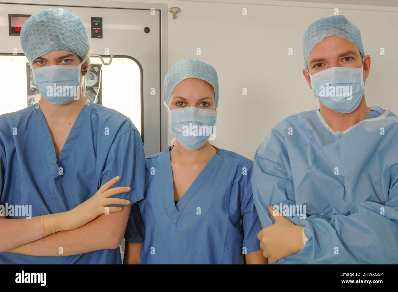 A team of surgeons, two men and one women, in bue operating caps, masks ...