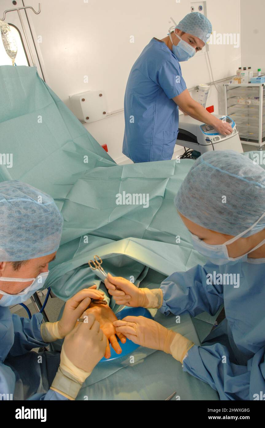 A team of three – a surgeon, a nurse and an anesthetist operate on a ...